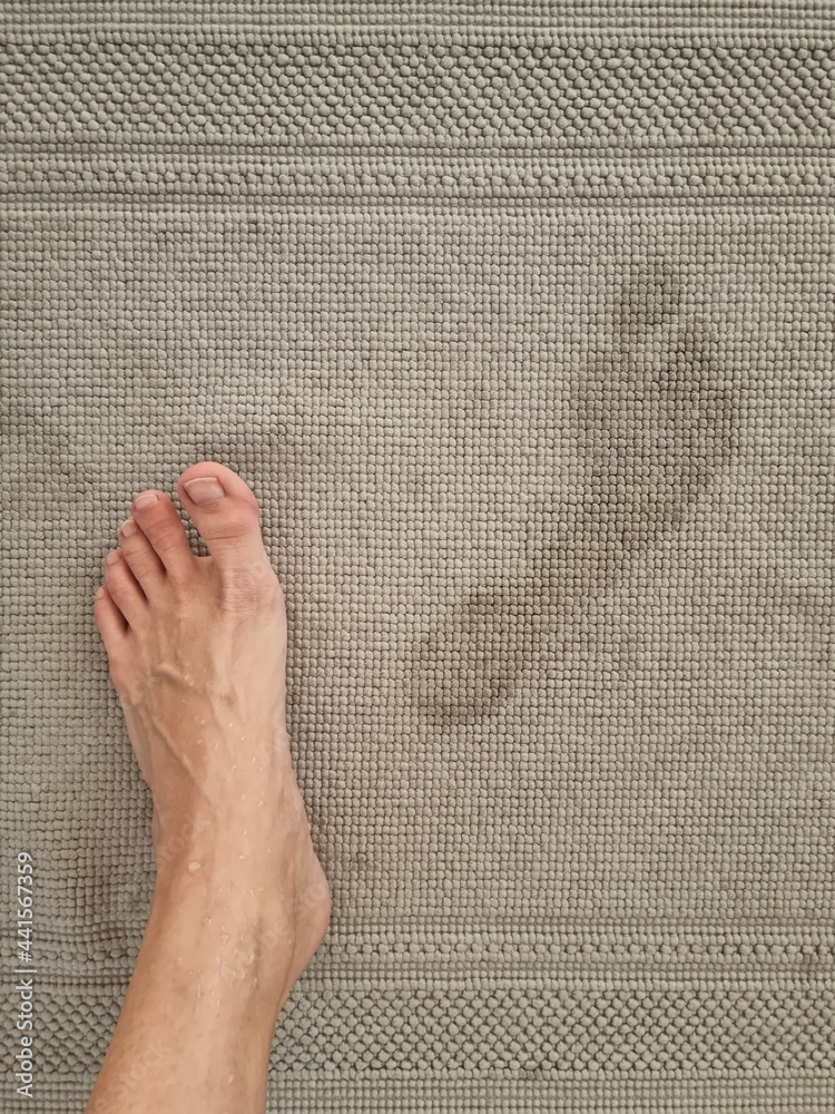 Female standing barefoot on the carpet. Wet footprint on the linen rug ...