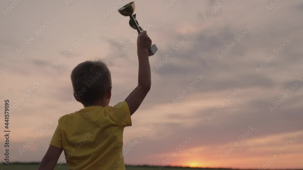 A child athlete celebrates his victory, joyfully raises his hands with ...