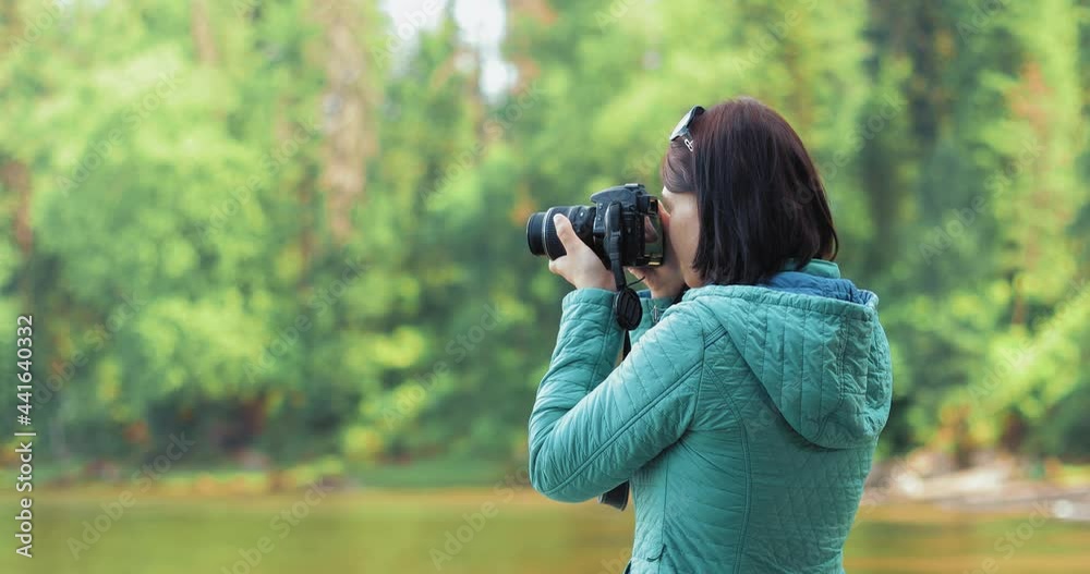The girl has a digital SLR camera in her hands. She takes nature photos ...