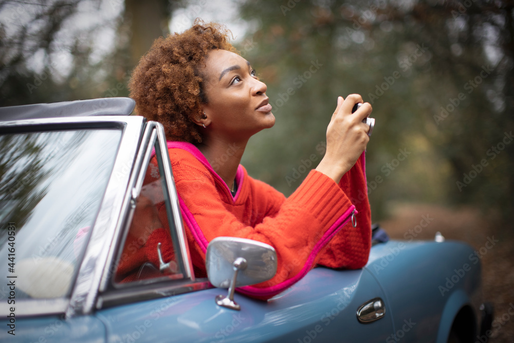 Young woman with digital camera looking up in convertible Stock Photo ...