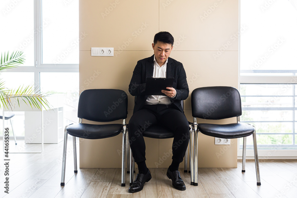 Asian businessman man, in the waiting room sitting on a chair near the ...