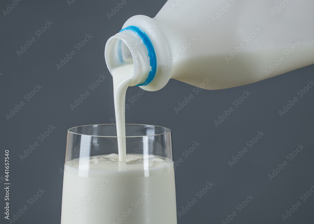 Kefir. Plain kefir pouring into a glass. White bottle with Yogurt ...