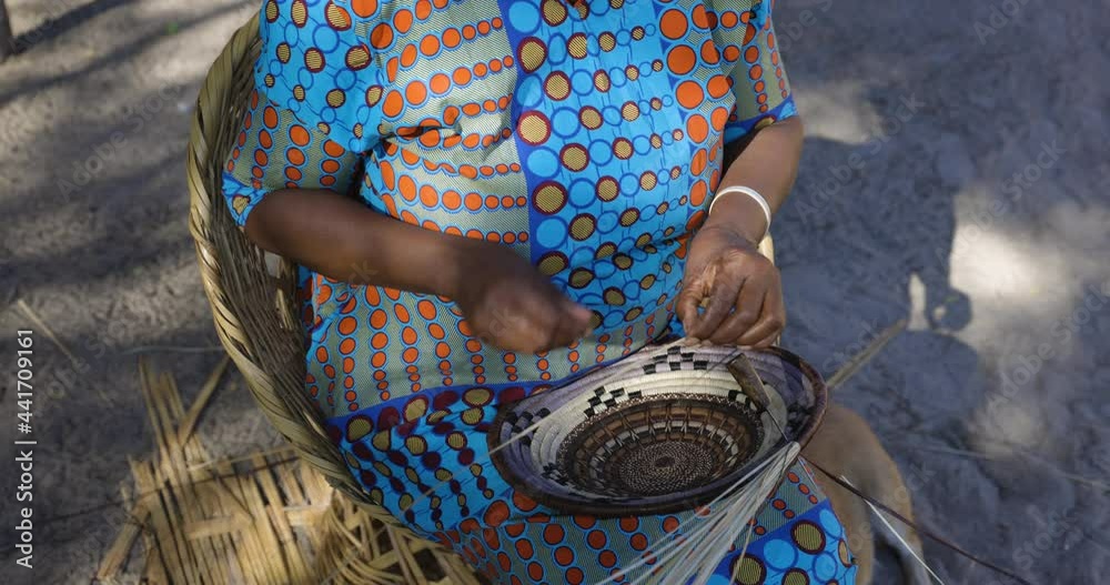 Close-up cropped view of a woman weaving a traditional basket made from ...