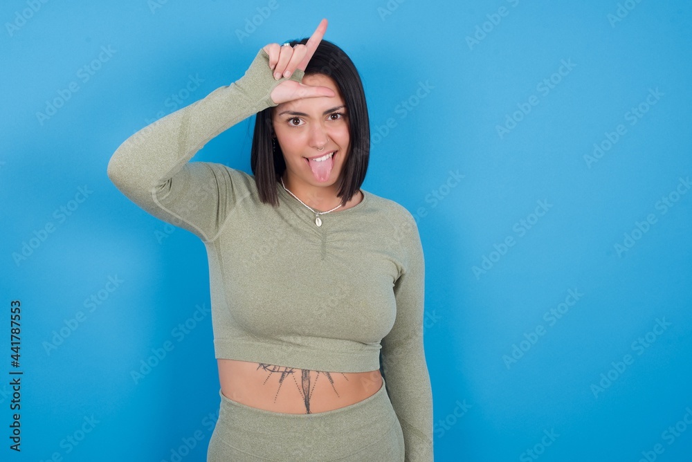 Funny Young beautiful sporty girl standing against blue background ...