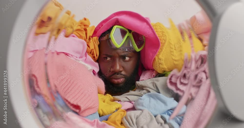 Laundry concept. Puzzled dark skinned bearded man poses against laundry ...