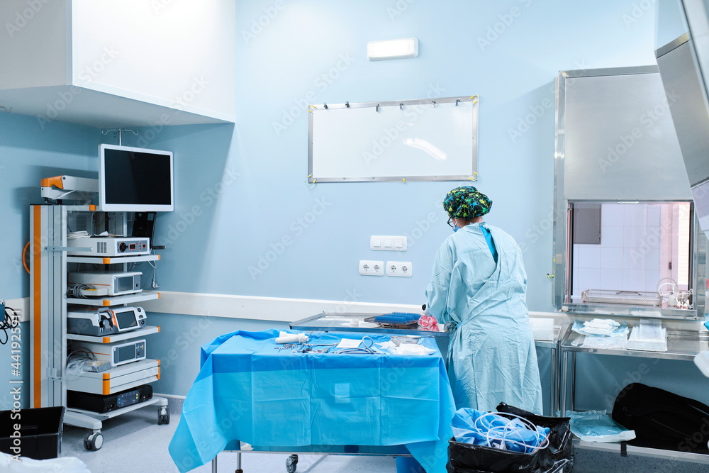nurse places sterile surgical supplies on an operating table for an ...