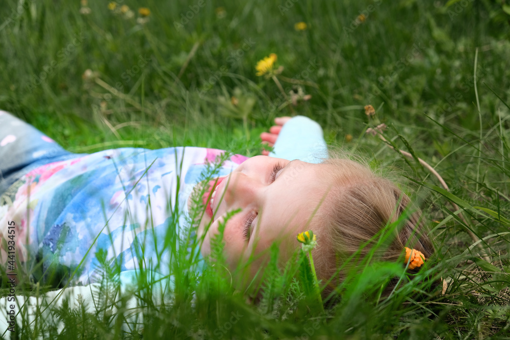 Little girl lying on grass lawn smiling. Summer fun outdoors. Happy ...