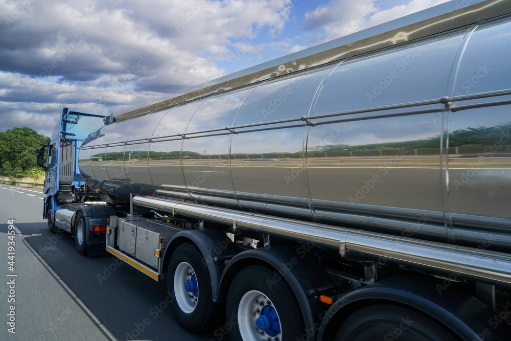 Tank truck with a shiny, reflective silver gas barrel driving on an ...