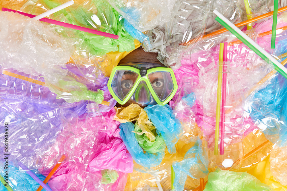 Foto de Dark skinned man drowned in various plastic litter wears ...