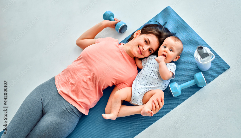 A sports mother is engaged with the child in fitness and yoga at home ...