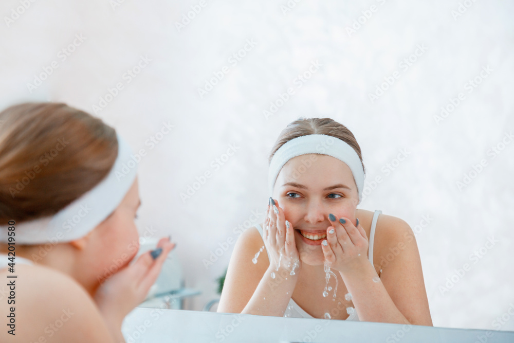 Foto de Young blonde woman washes face pure water in bathroom sink ...