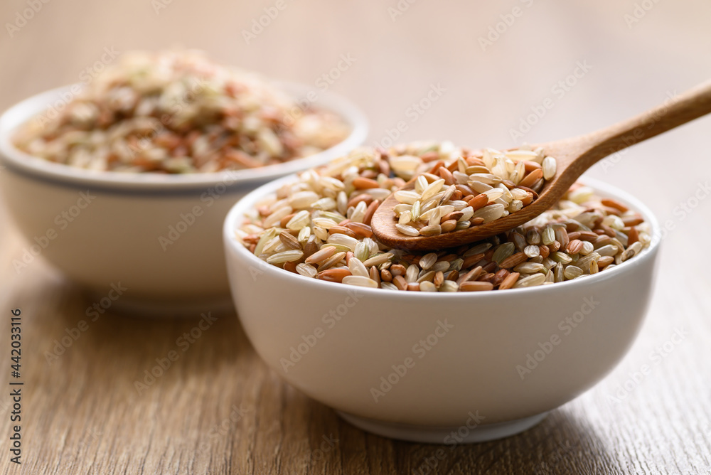 Organic Thai highland brown rice grain in a spoon and bowl on wooden ...
