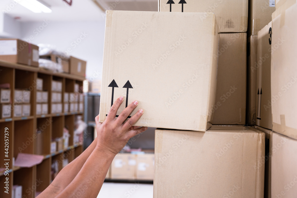 Close up hands of warehouse worker lifting box in storage room.Man ...