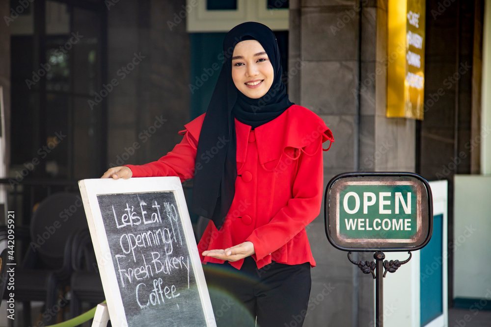 Muslim lady standing outside the halal restaurant with open sign to ...