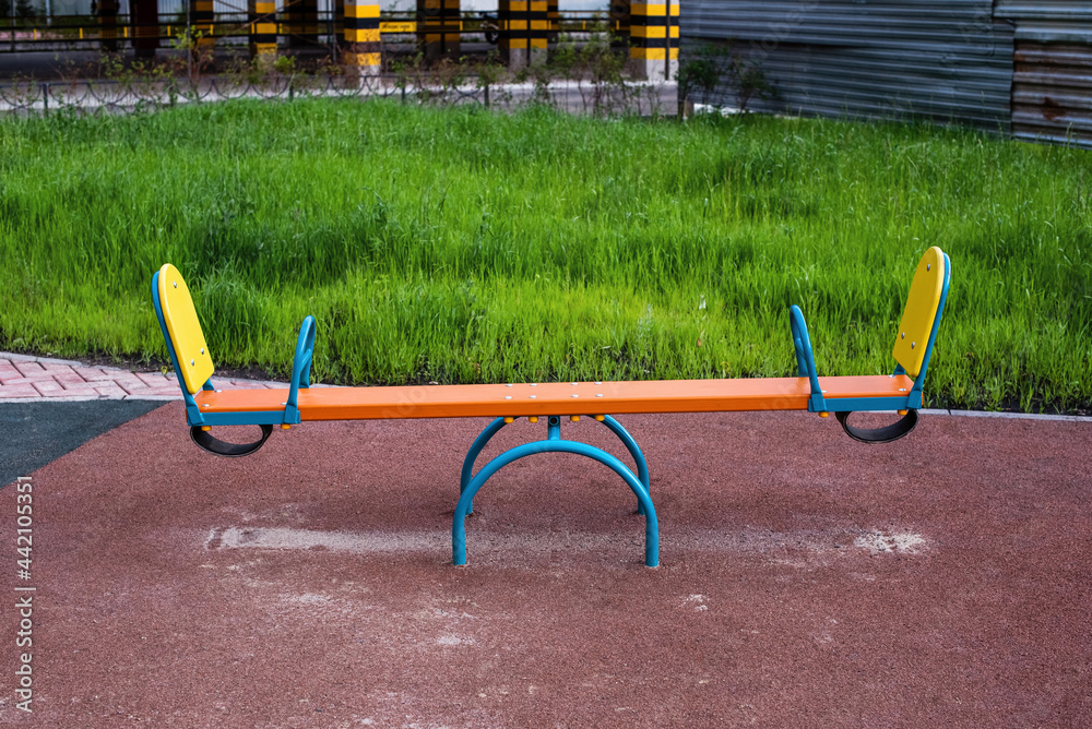 Swing balancer on the playground, green grass, parking and metal fence ...
