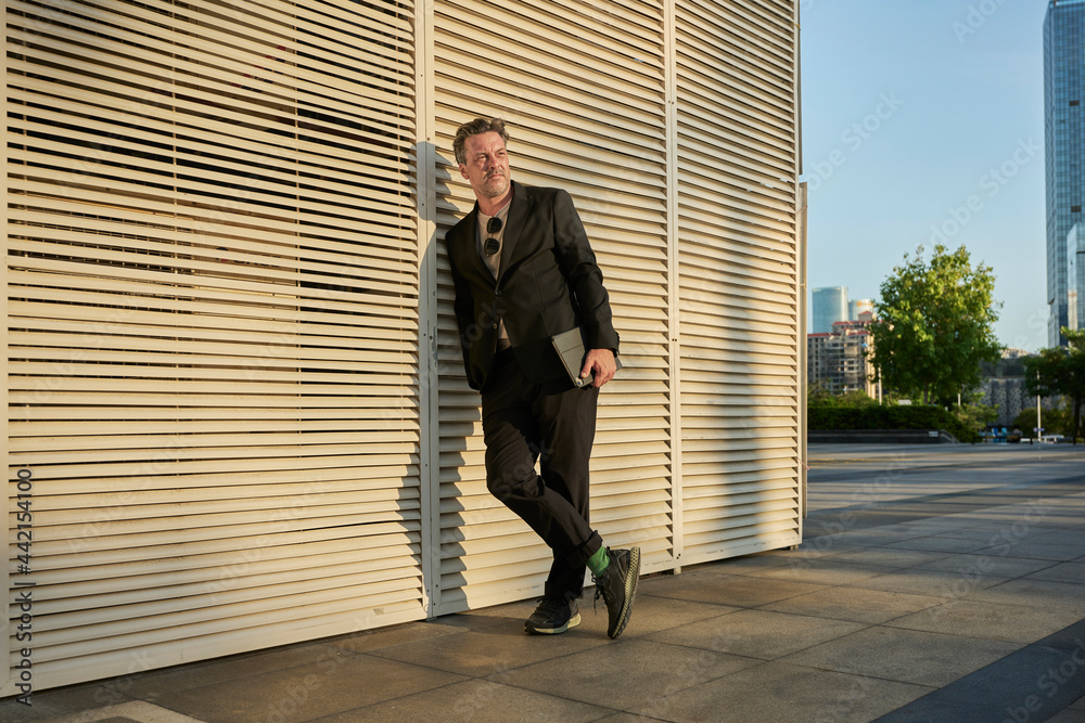 Business man standing up outside of office building in sunset time ...