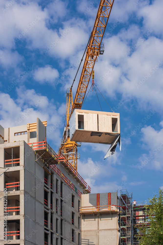 Crane lifting a wooden building module to its position in the structure ...