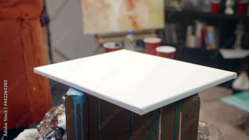 Women artists is pitting new canvas on the painting table to start ...