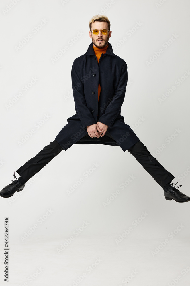 energetic man jumped up with legs wide apart in a black coat Stock ...