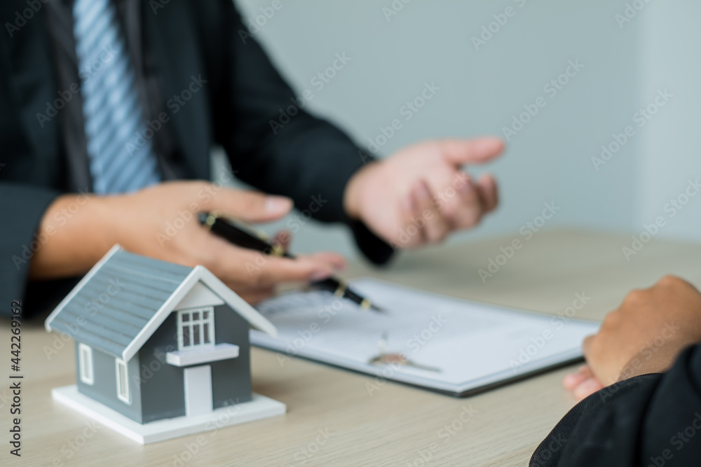 A real estate agent with House model is talking to clients about buying ...