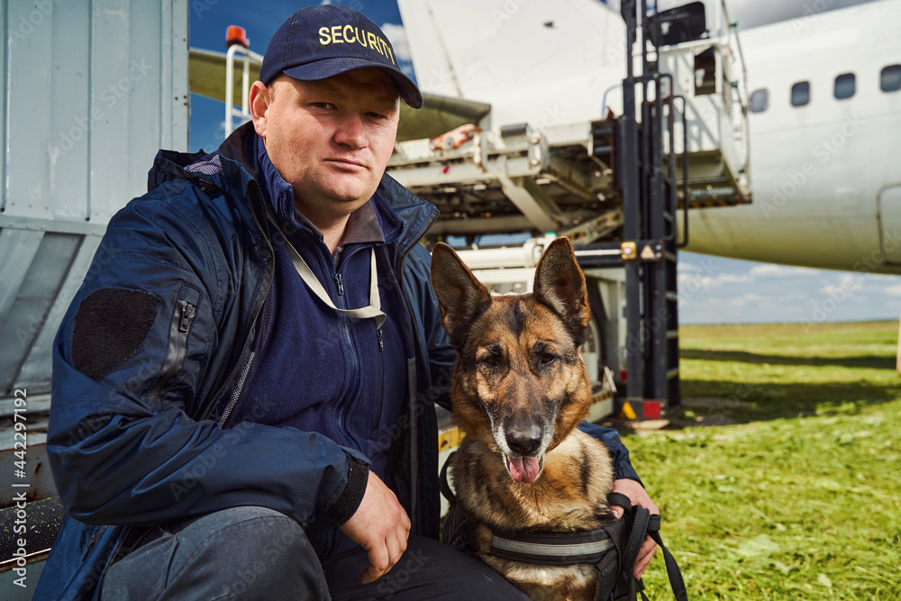 Male security guard hugging dog at airfield Stock Photo | Adobe Stock