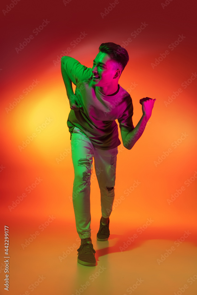 Portrait of Caucasian young man dancing, dancing isolated on orange ...