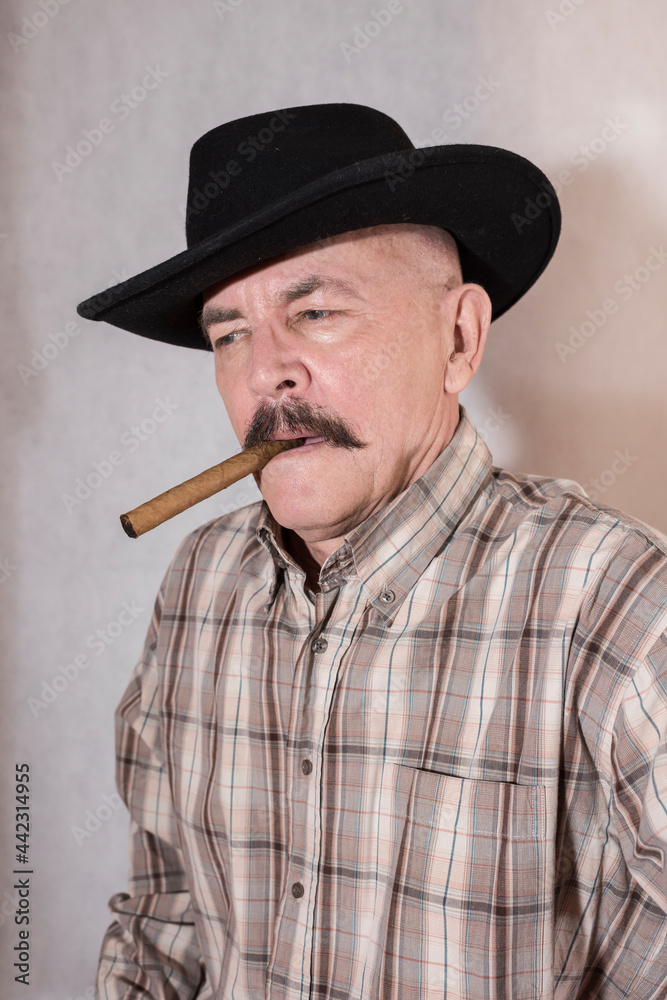 The cowboy with mustache, in a black hat smoking a cigar Stock Photo ...