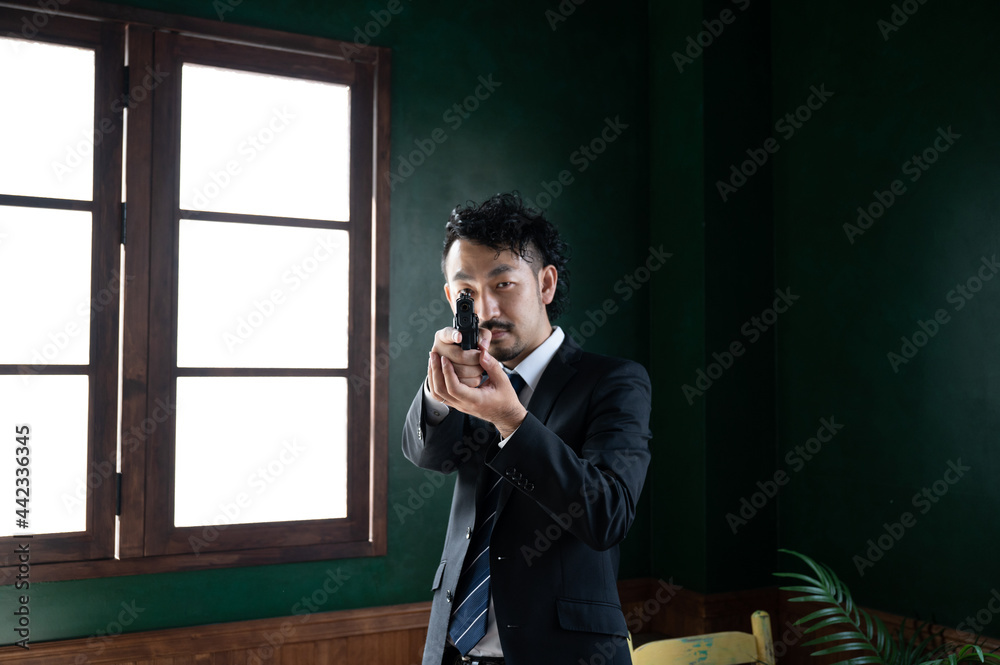 Image of a cool Asian spy-looking guy pointing a gun at the front Stock ...