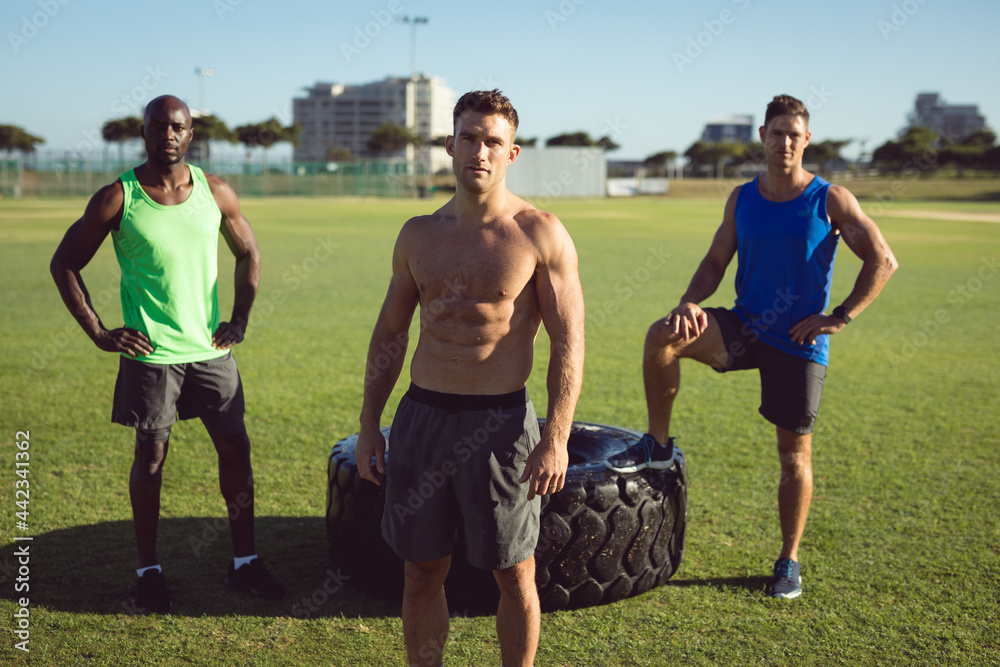 Portrait of diverse group of shirtless men exercising outdoors standing ...