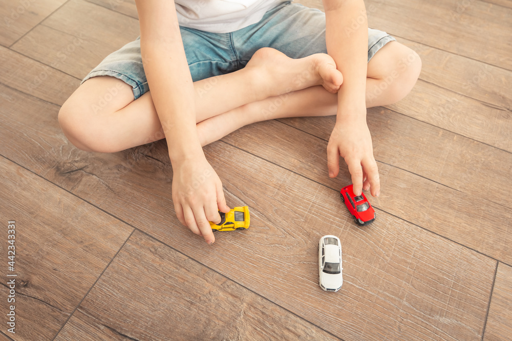 Little boy playing barefoot with toy cars on wooden floor in house ...