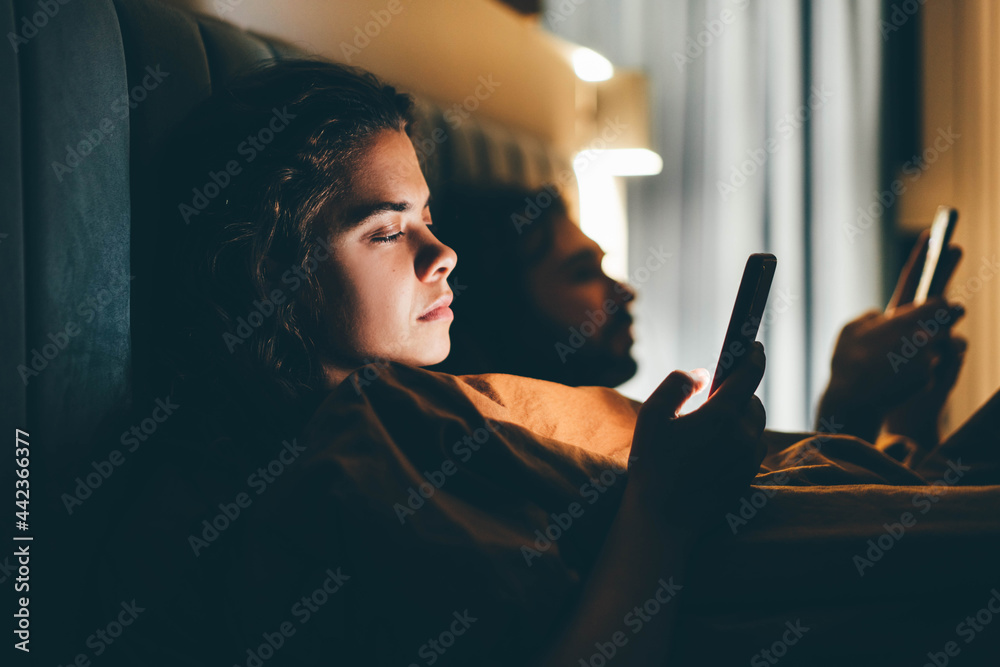 Couple with smartphones in their bed. Mobile phone addiction. Bored ...