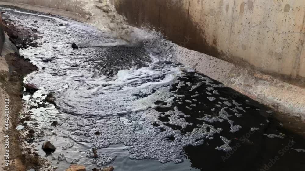 Industrial sewage polluting pipe. Black dirty flow. Dirty gutter water ...