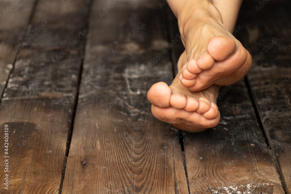 female bare feet on the old wooden floor of the house, feet on the ...