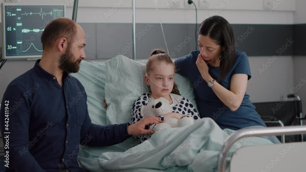 Sick daughter with oxygen nasal tube resting in bed after suffering ...