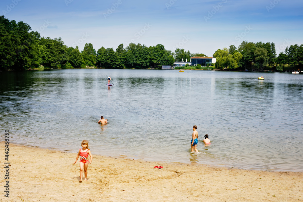 Little blond preschool girl having fun with splashing in a lake on ...