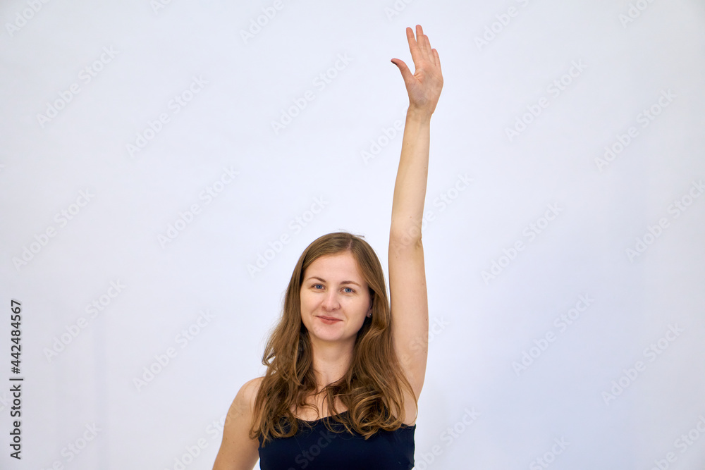 Raise your hand up. A beautiful Caucasian woman stands on a white ...