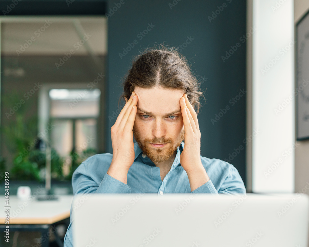 Concentrated male company employee with fingers on temples and looking ...