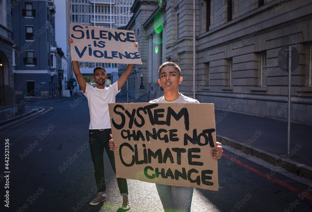 Two mixed race male friends carrying hand painted protest signs with ...