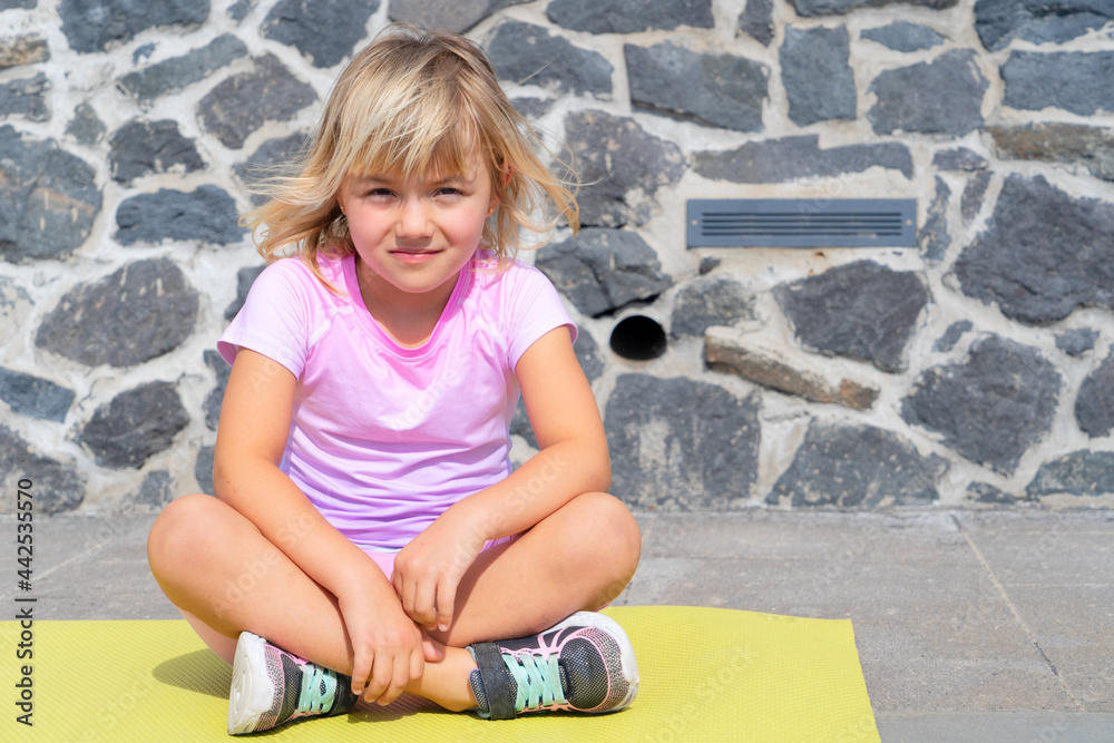 Cute happy little girl in sportswear smiling at camera while while ...