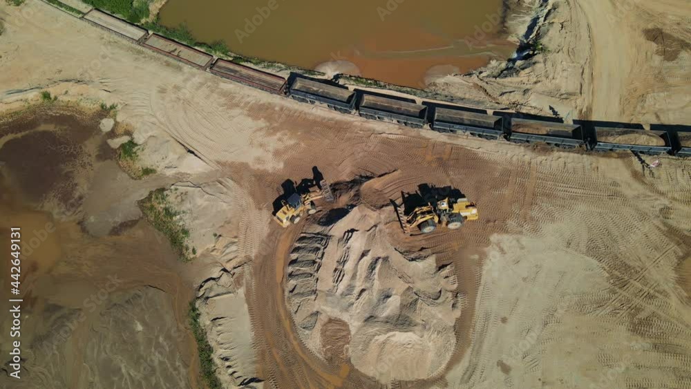 Wheel loader loading sand it to the freight train. Mining work in open ...