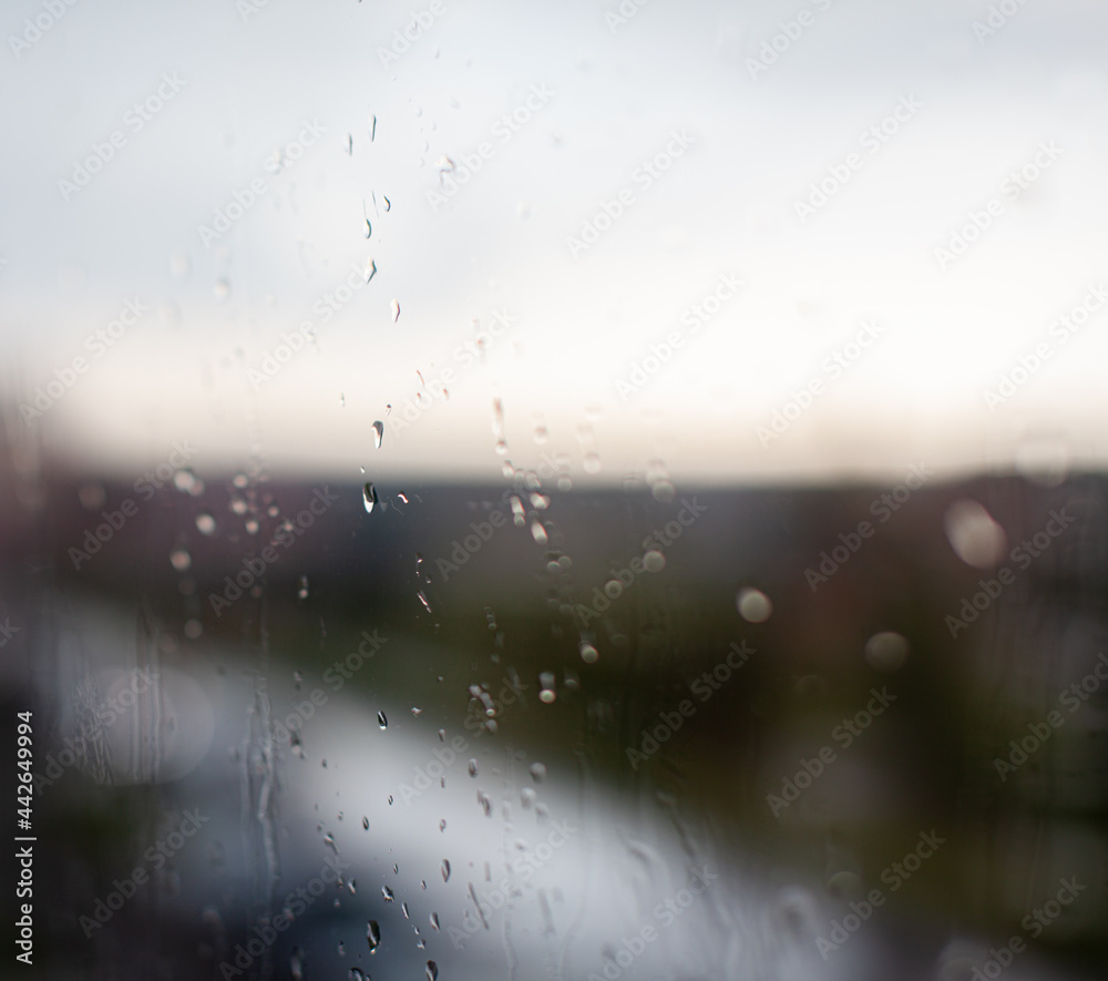 Rainy day through the window on cloudy grey sky and city buildings ...