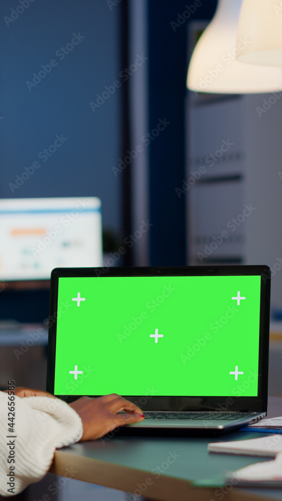 African manager typing at laptop with chroma key display during night ...