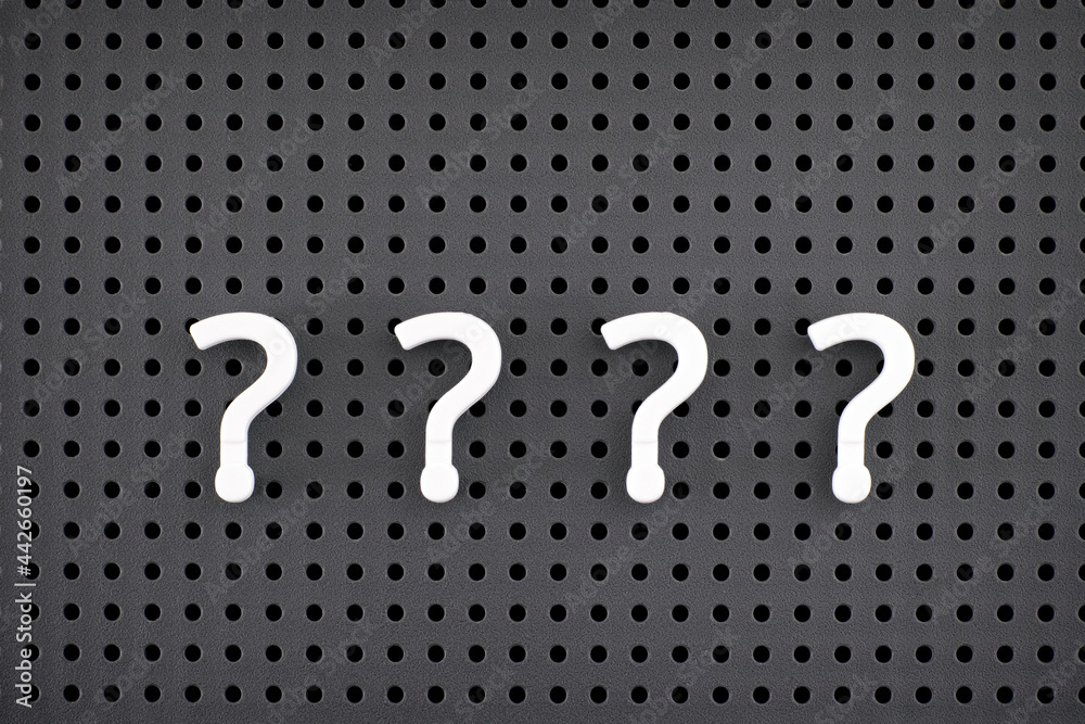 Four question marks spelled out by white symbol on gray pegboard Stock ...