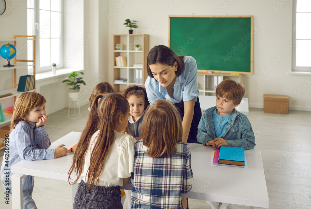 Group of children performs tasks together with a young woman, a primary ...