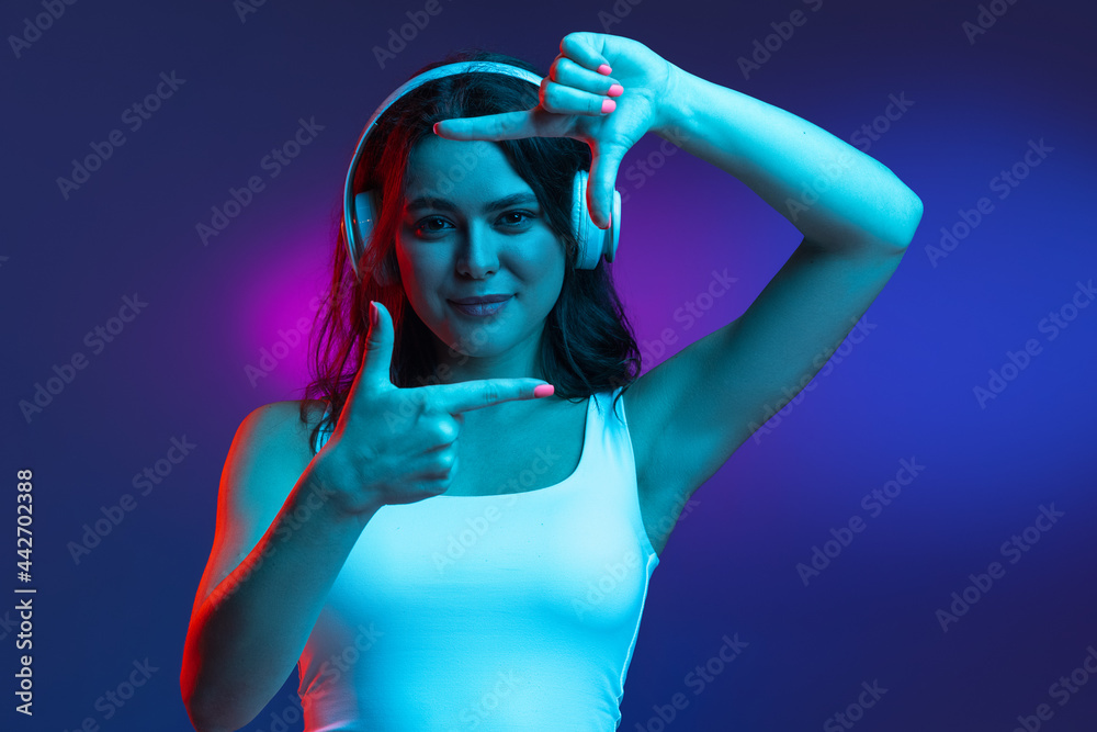 Caucasian young woman's portrait on dark studio background in neon ...