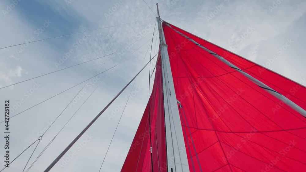 The bottom view on a mast of the sailboat with a sail of red color, a ...