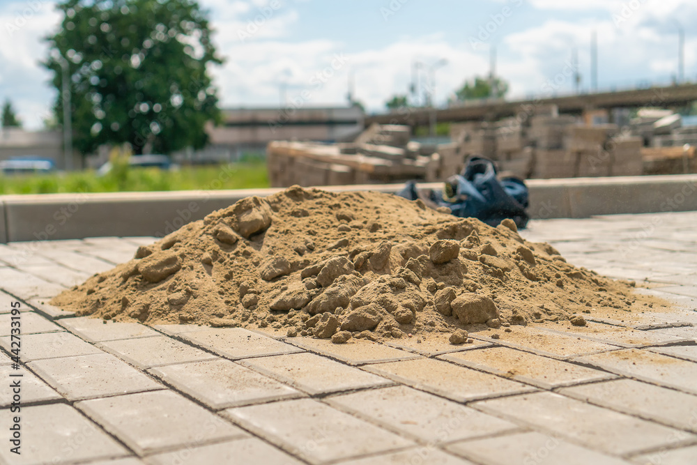 Close-up of a pile of sand lying on the new sidewalk to seal the seams ...