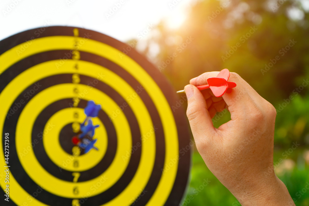 Hand with red arrow darts to throw on dartboard hanging at the tree ...