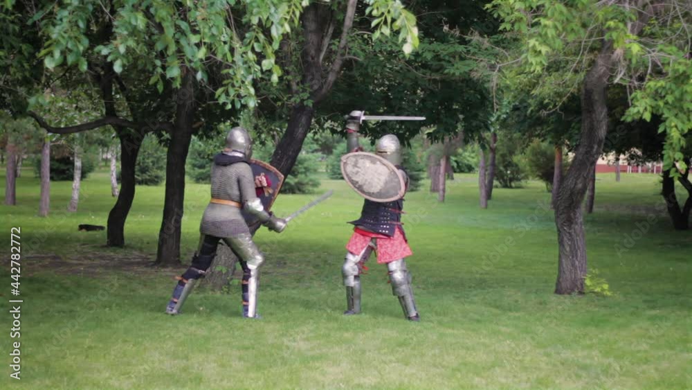 Battle of two medieval warriors in full sets of armor with swords and ...