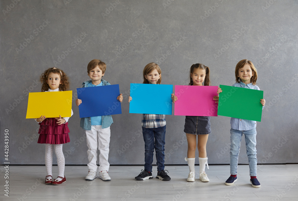 Team of four cute little children showing colorful blank mockup sign ...